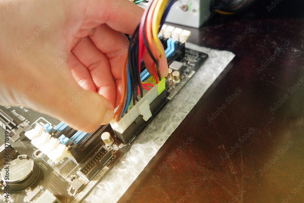 Man's hands plugging in the ATX power plug of a computer motherboard ...