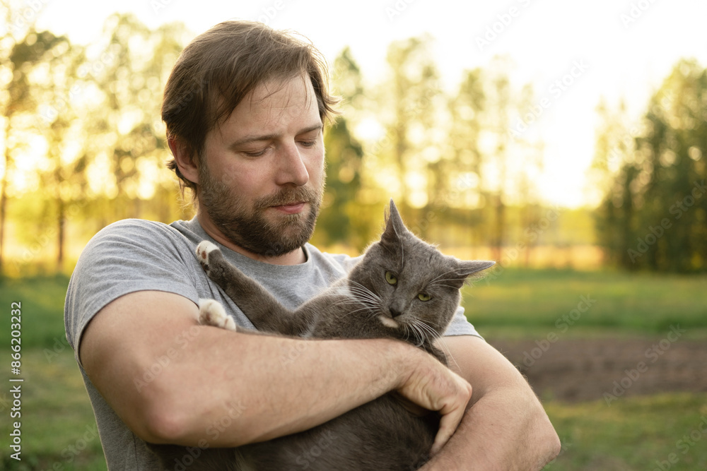 Adult Man holding in hand his cat outdoors. Handsome guy holding cat ...