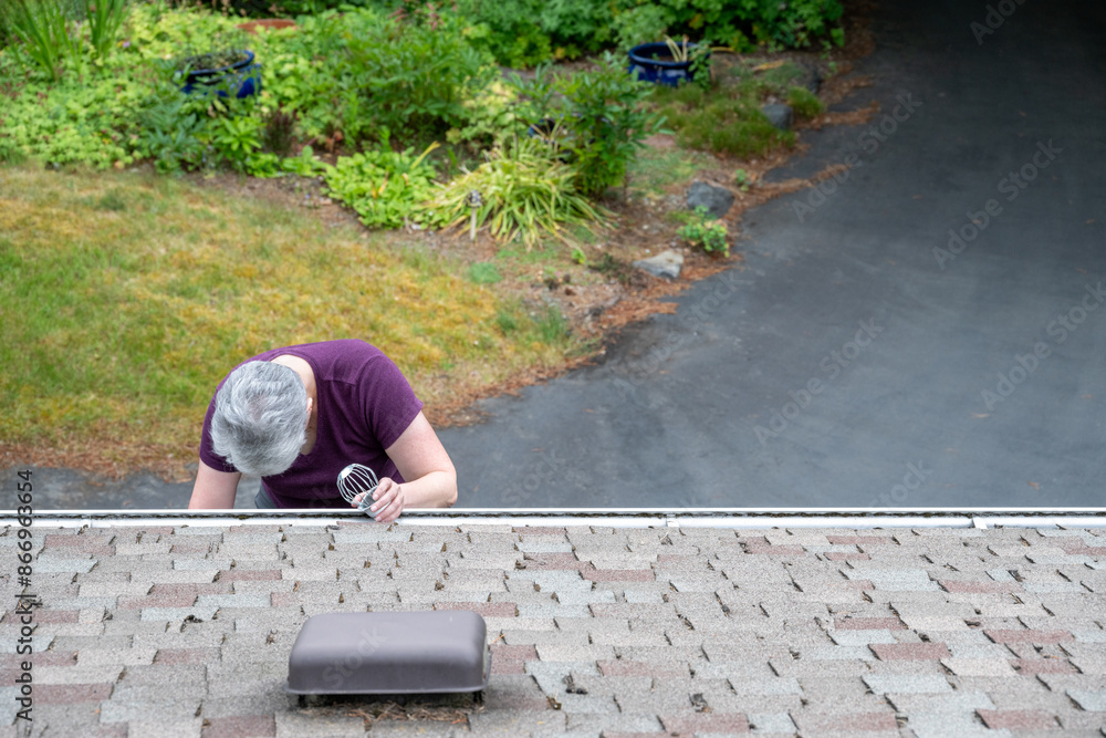 Middle aged white woman with gray installing a downspout filter in a ...
