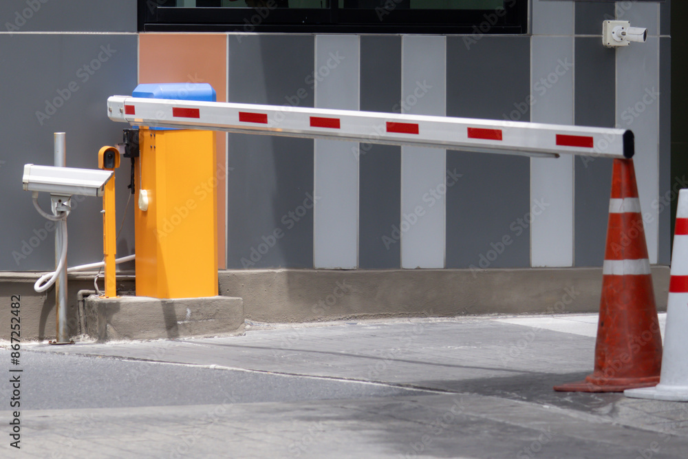 A red and white traffic barrier with a camera on top of it. A yellow ...