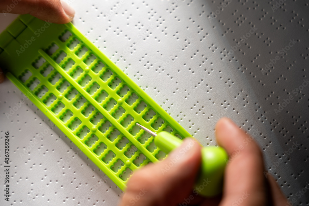 Close up Hand of a blind person writing some braille text on page paper ...
