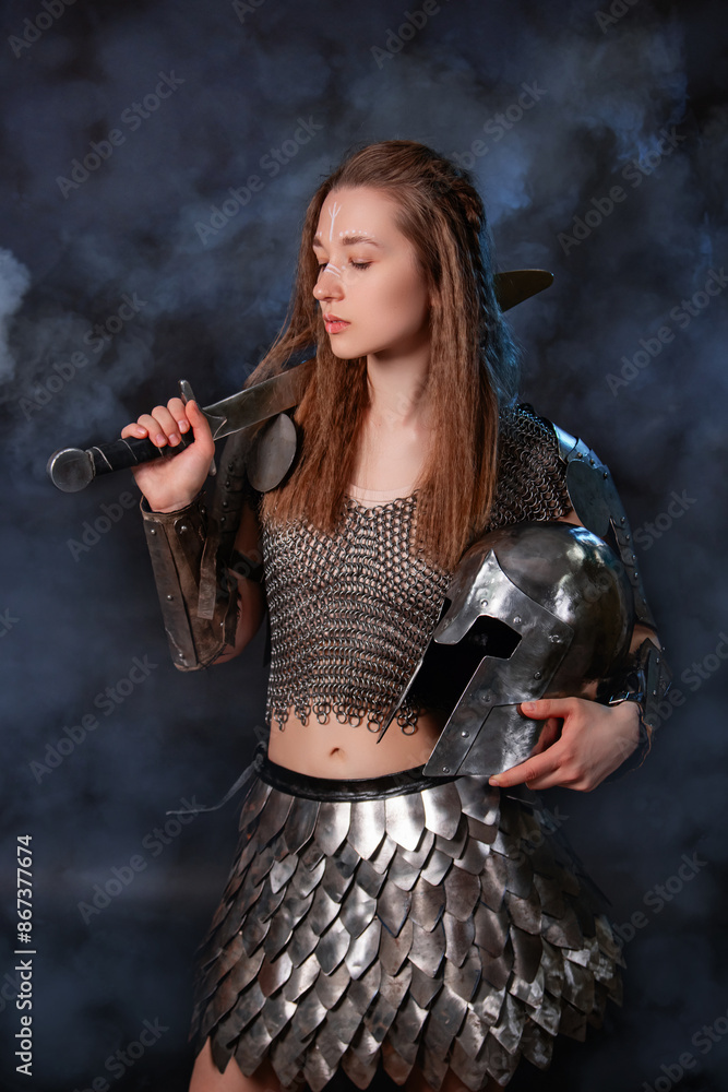 Portrait of a medieval female warrior in armor with a sword and helmet ...