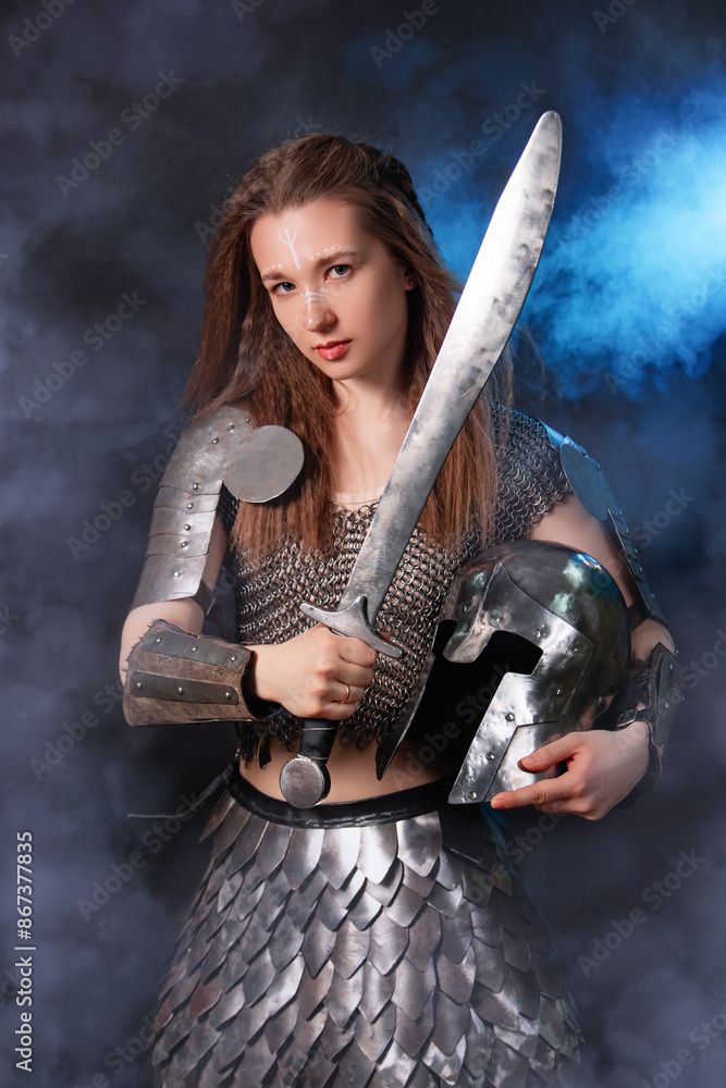 Portrait of a medieval female warrior in armor with a sword and helmet ...