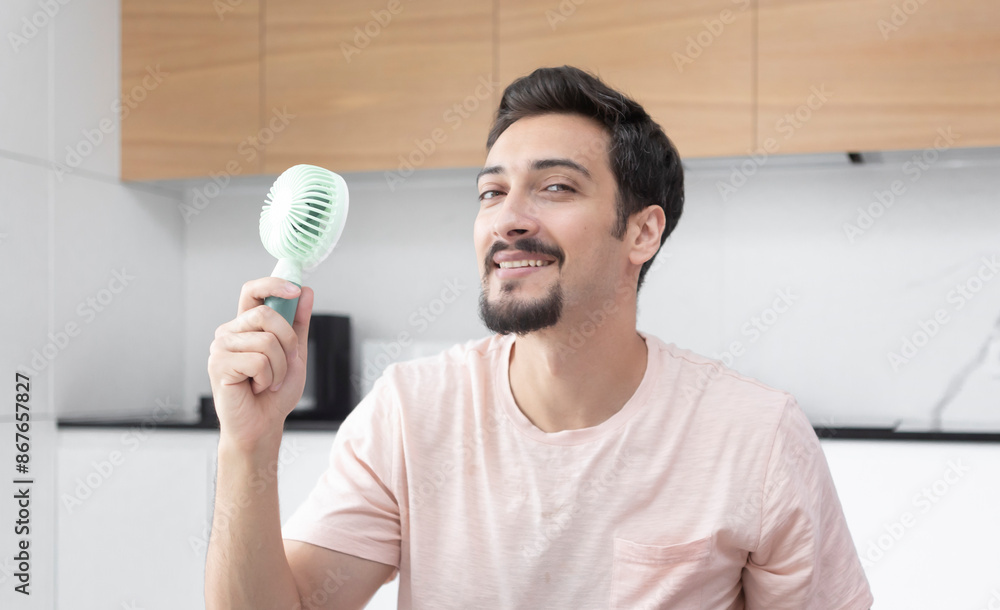 Tired and overheated man suffering from a heat attack uses an electric ...