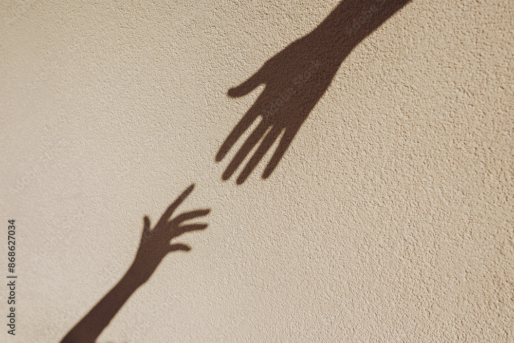 Shadows of hands reaching each other on the wall. Abstract blurred ...