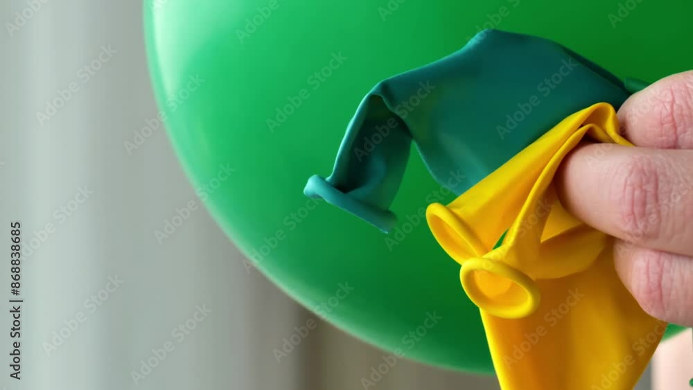 green balloon is inflated and green and yellow balloons in hand on ...