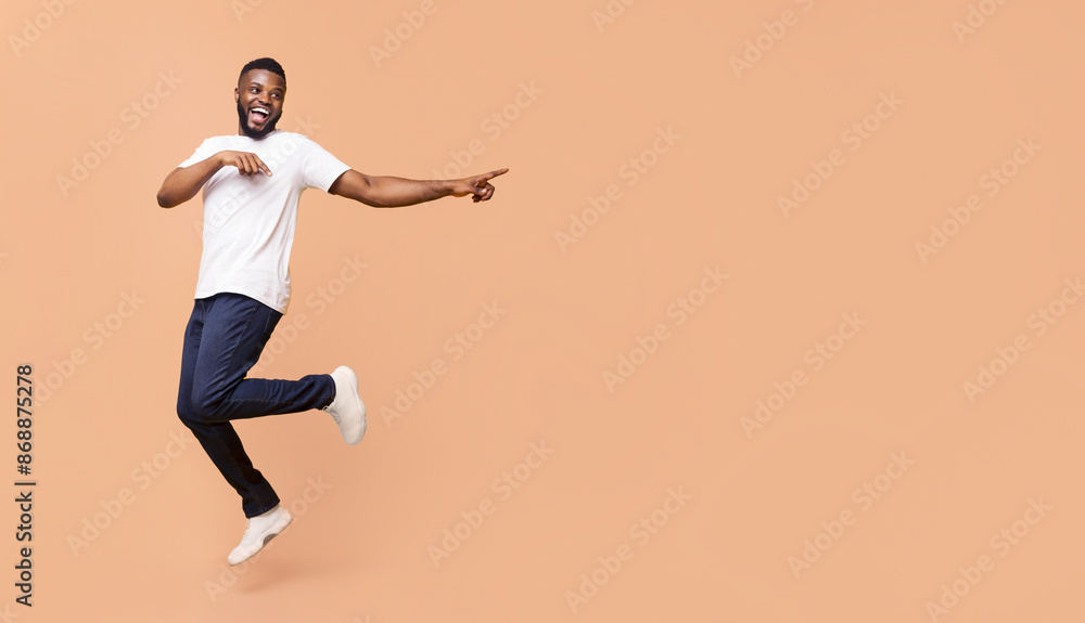 A happy African American young man is jumping in the air while pointing ...