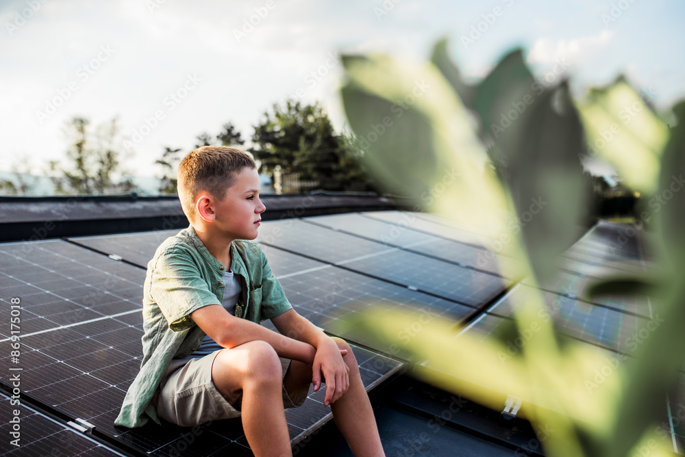 Cute boy sitting on roof with solar panels, looking at surrounding ...