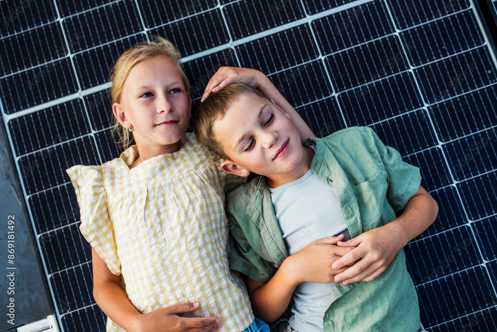 Top view of two young siblings lying on roof with solar panels. Rooftop ...