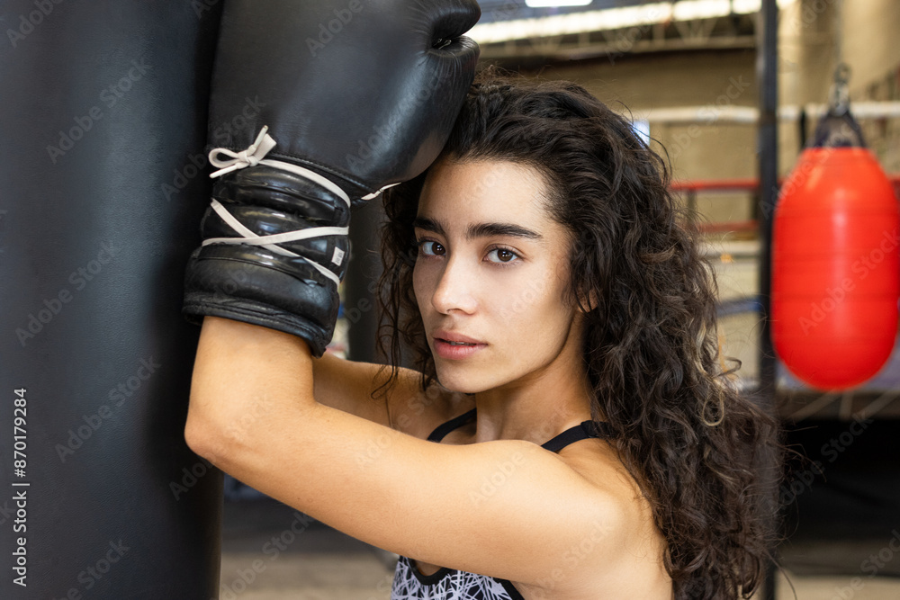 Confident and strong female boxer looking at the camera while leaning ...