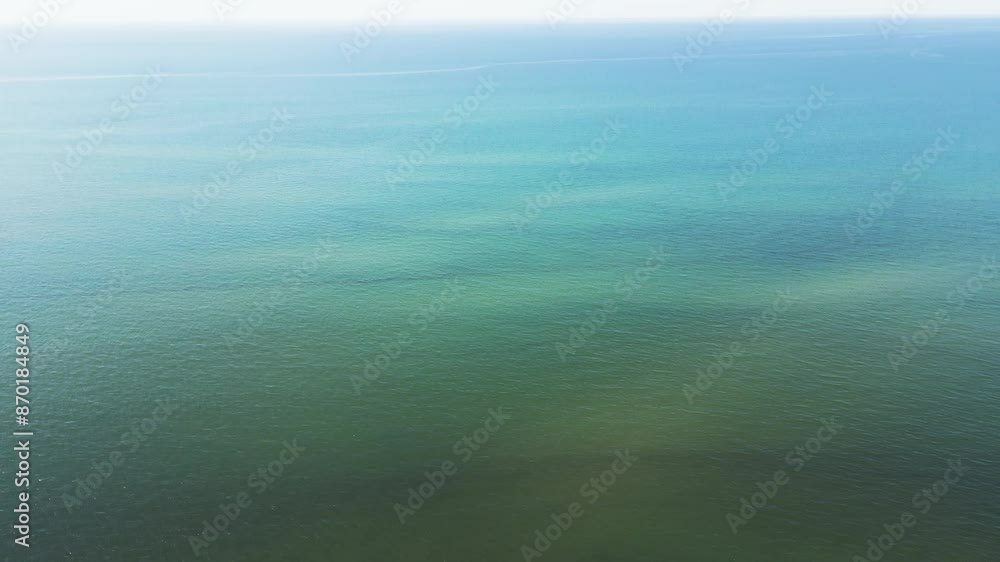 Drone tilt down across green calm atlantic ocean water and ripples ...