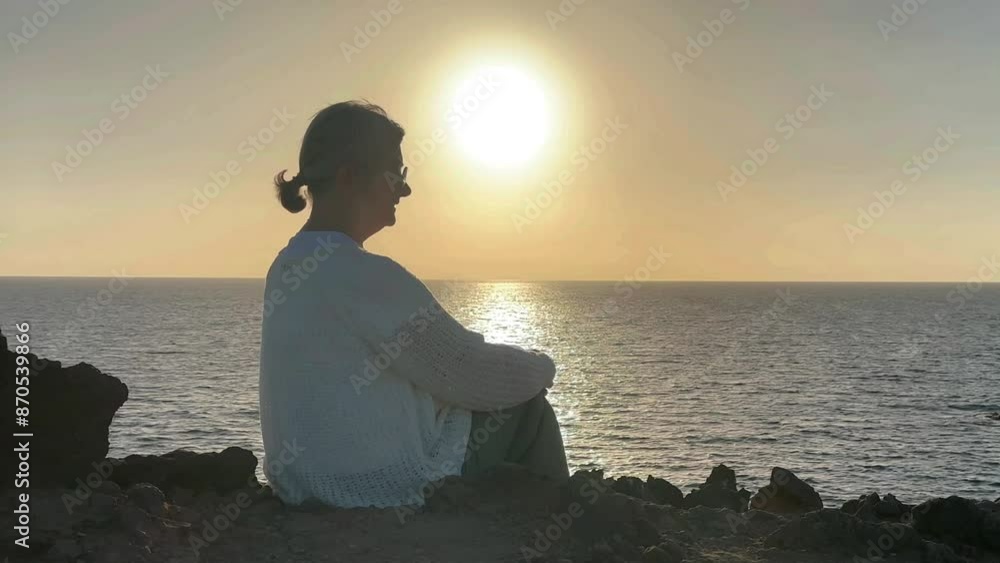 Back view of relaxed senior woman sitting face the sea admiring the ...