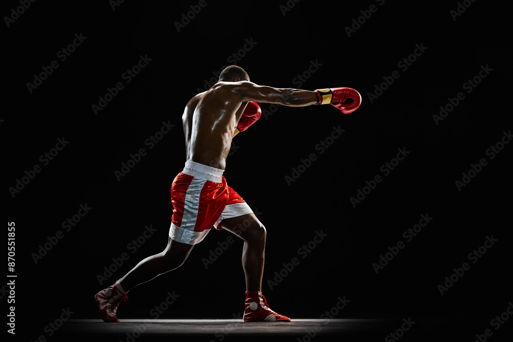 Jab punch. muscular shirtless man, boxer in red uniform practicing ...