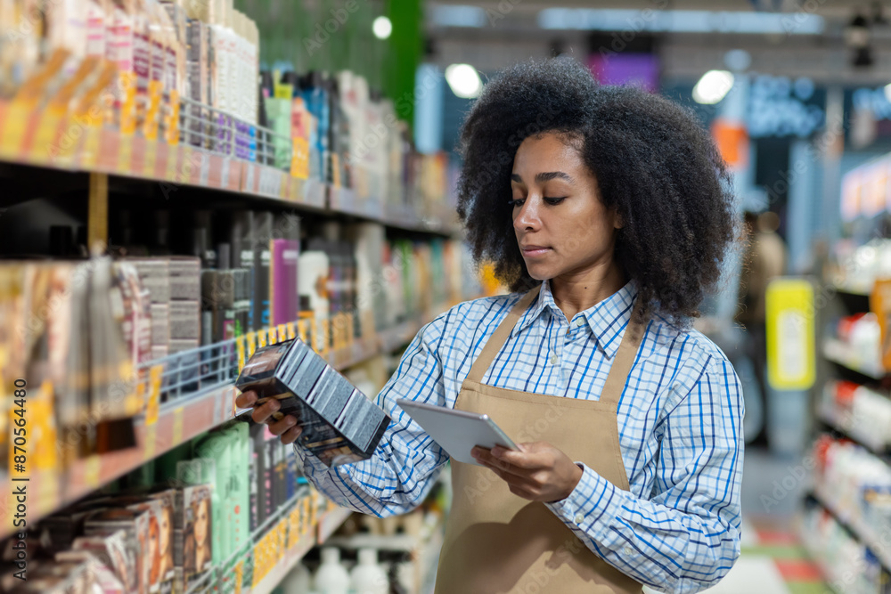 Store employee in apron checking inventory and scanning a product with ...
