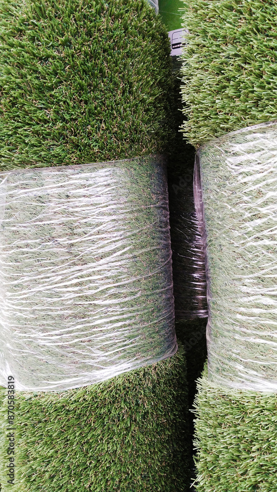 Rolls of green artificial grass carpet or wall in supermarket ...