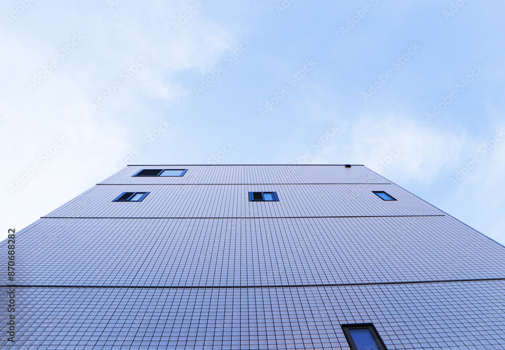 Bottom view of rectangular high-rise building. Blue sky with white ...