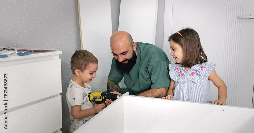 Dad with kids assembling a wardrobe on his own at home in the children ...