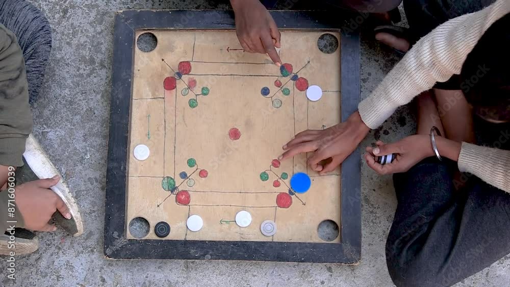 Indian village children are playing a carrom board game outdoors on a ...
