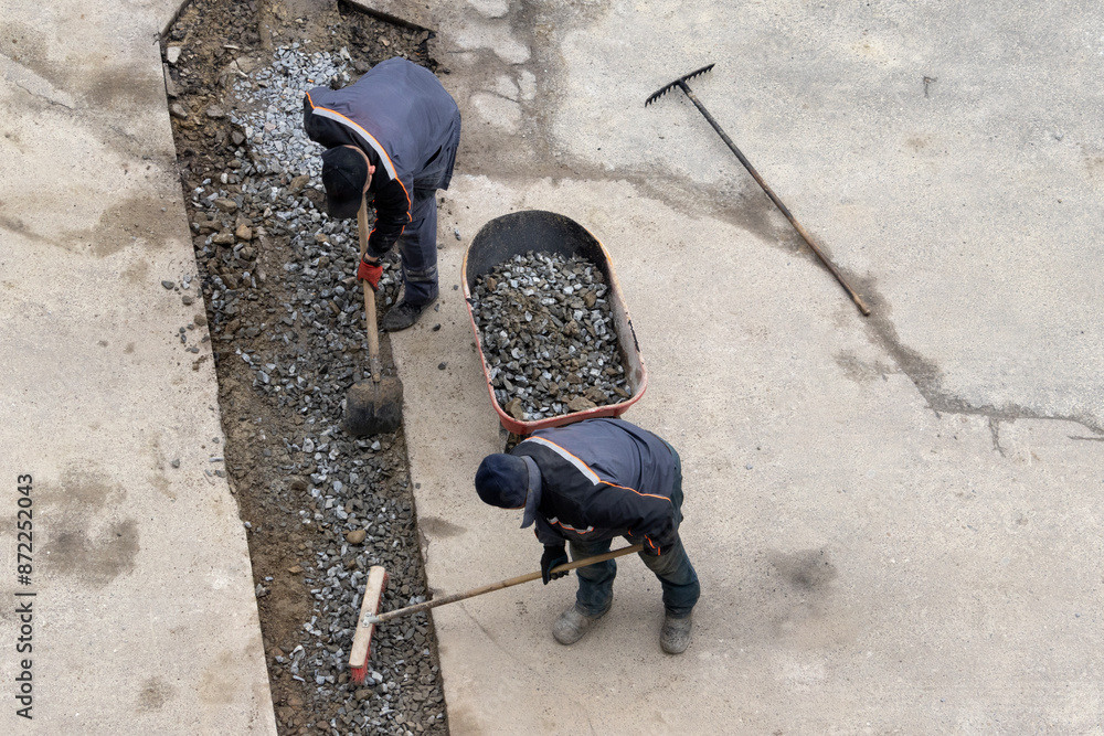 Workers of the road service are preparing a base of crushed stone for ...