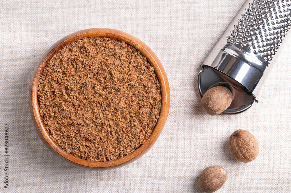 Nutmeg powder, ground nutmeg in a wooden bowl on linen fabric. Fragrant ...