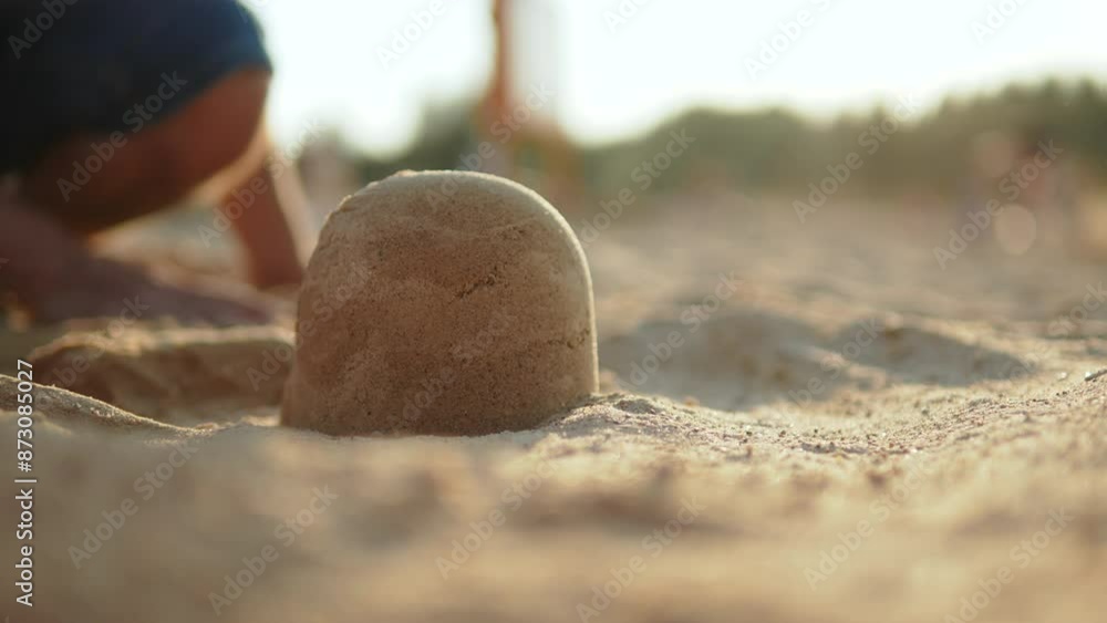 Smooth sand tower made from child mold on sunny beach closeup. Teenager ...