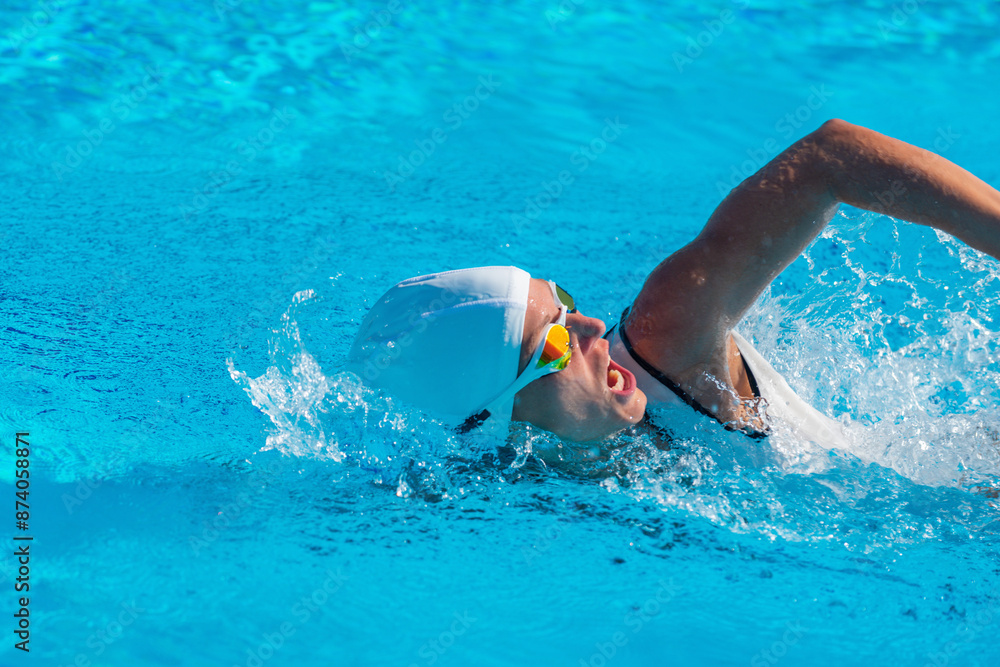 Female swimmer in white swim cap and goggles performing freestyle ...