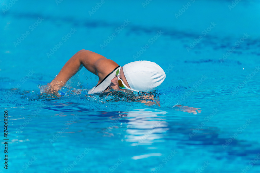 Female swimmer in white swim cap and goggles performing freestyle ...