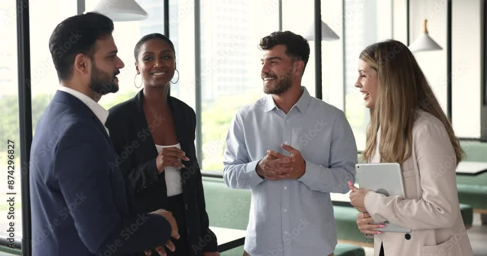 Diverse team of young business colleagues chatting in office hall ...