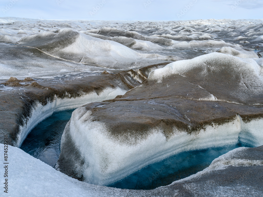 Drainage system on surface of ice sheet. Brown sediment on the ice ...