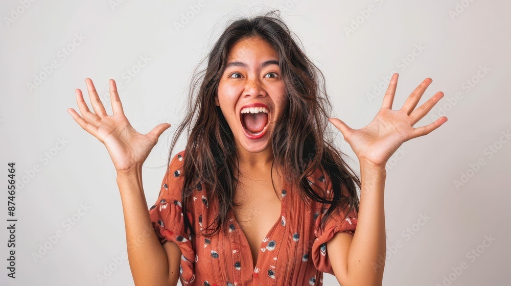 beautiful young asian woman with open mouth raising hands in a ...