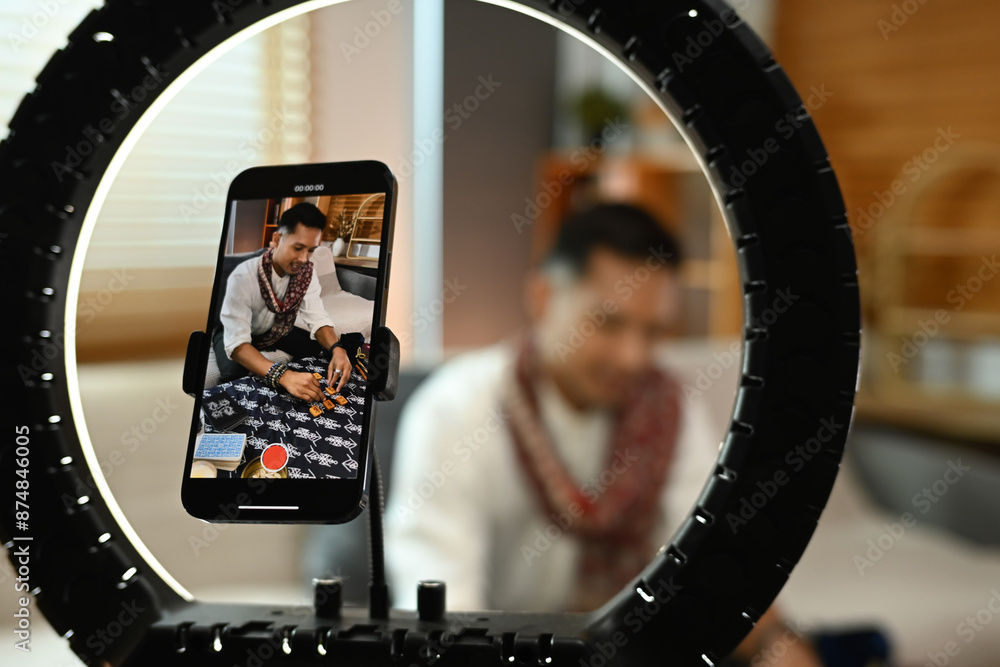 Fortune teller showing wooden runes in front of smart phone camera while having an online ...