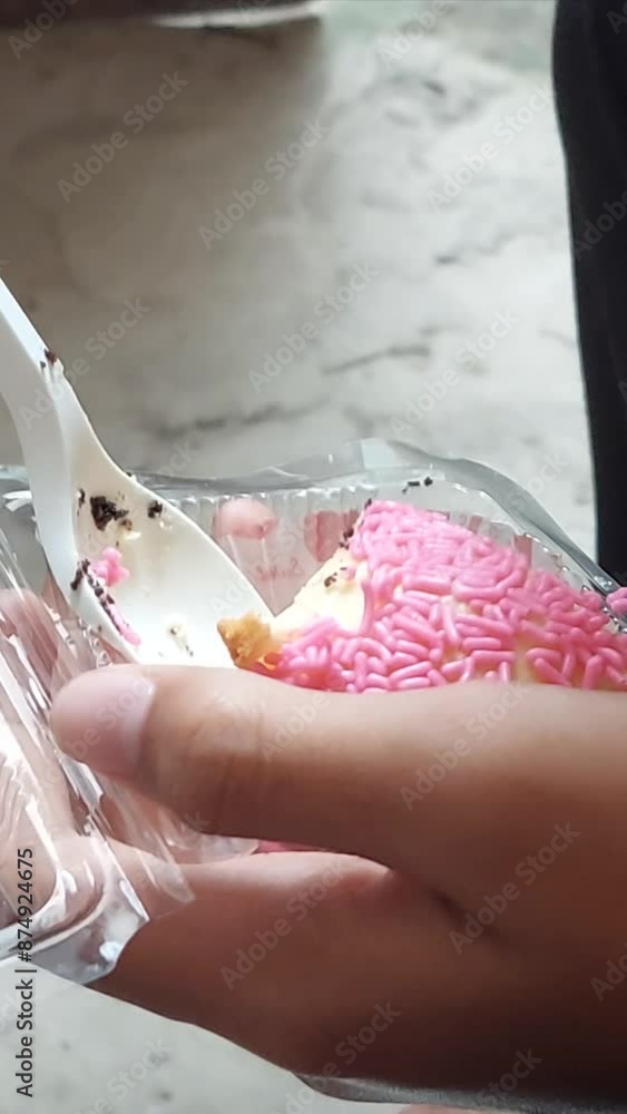 Close-up view of a hand holding a forkful of sprinkle-topped cake. The ...