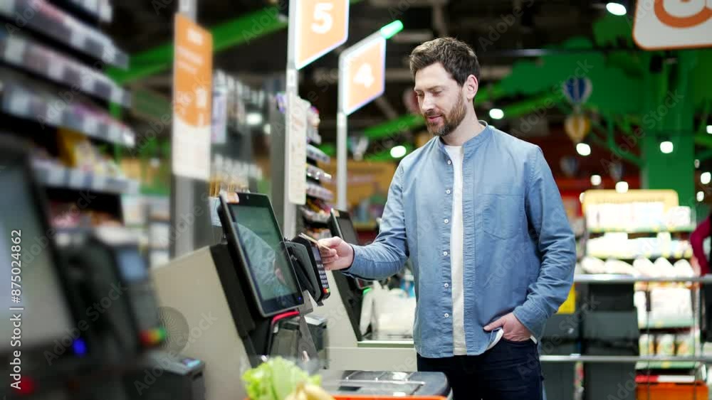 Male customer using a self-service cashier checkout in a supermarket ...