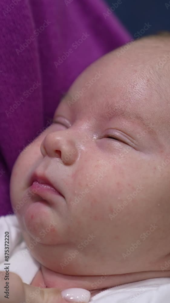 Sleepy newborn kid doesn't want to wake up lying in mum's hands. Mother ...