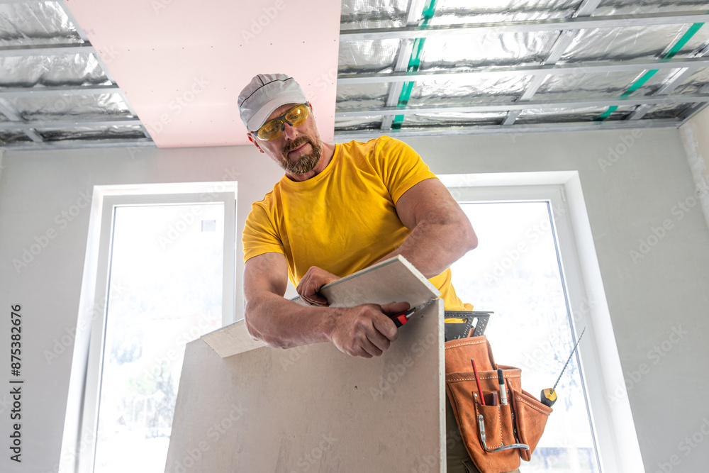 The worker make a plasterboard ceiling. He doing adjusts a size of the ...