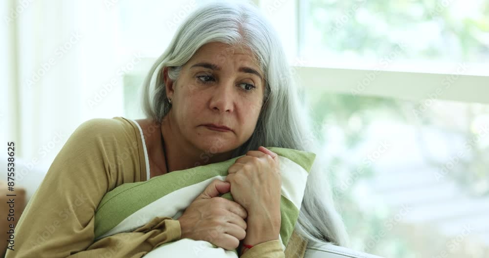 Sad depressed old lady with long naturally grey hair embracing pillow ...