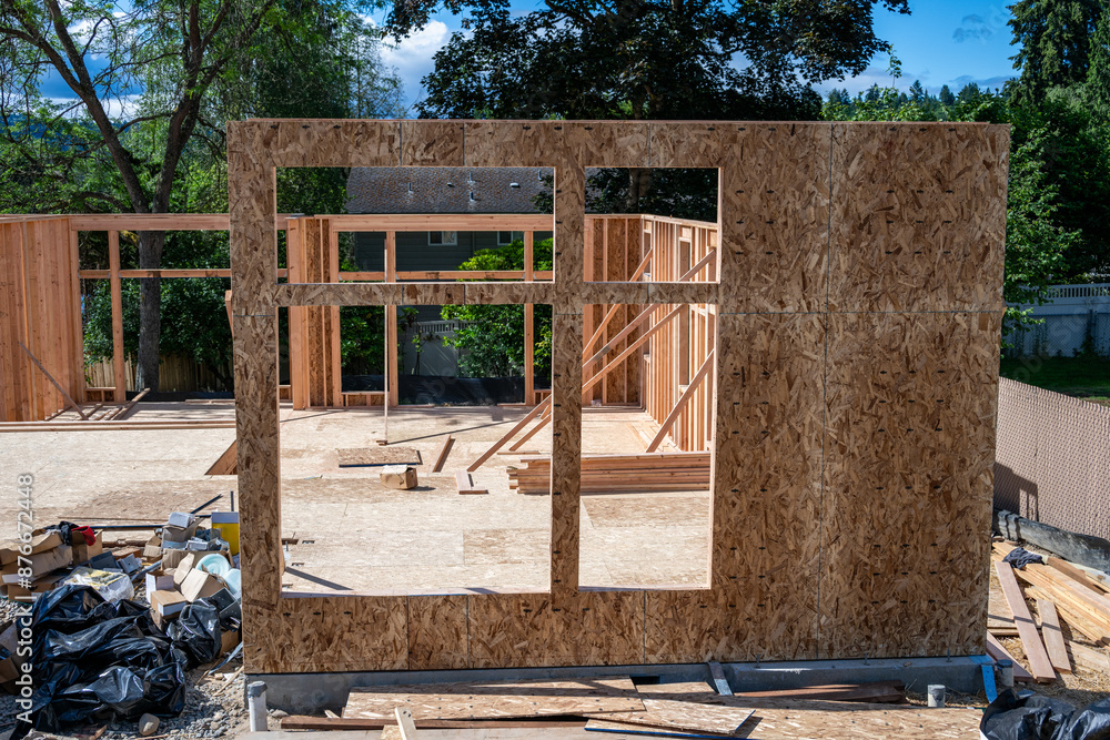 Wood framing started on new home construction, stacks of delivered ...