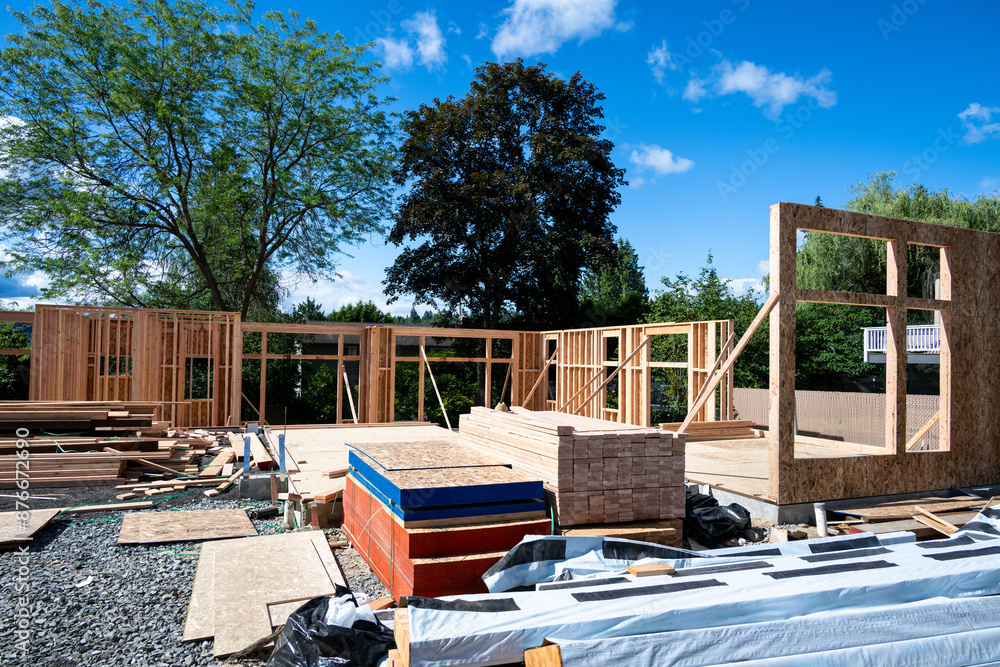 Wood framing started on new home construction, stacks of delivered ...