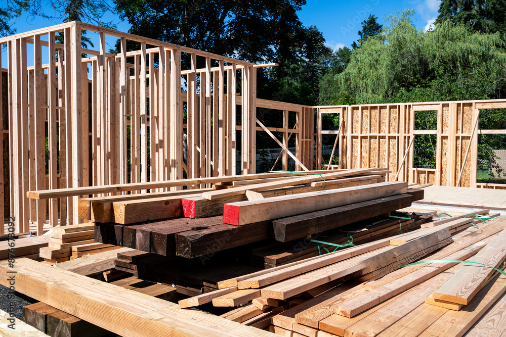 Wood framing started on new home construction, stacks of delivered ...