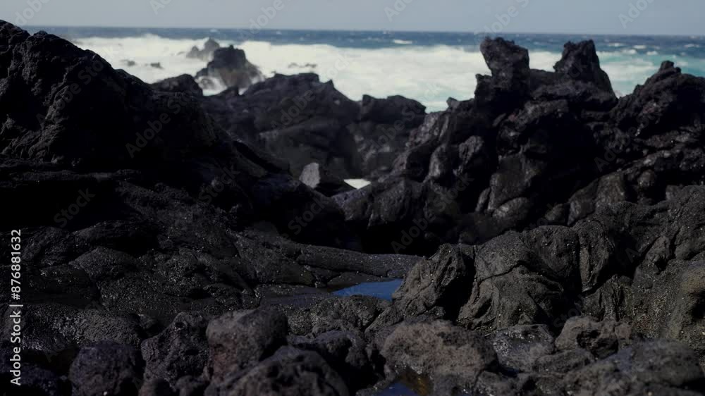 Dramatic view of black lava rocks foregrounding the violent, foamy ...