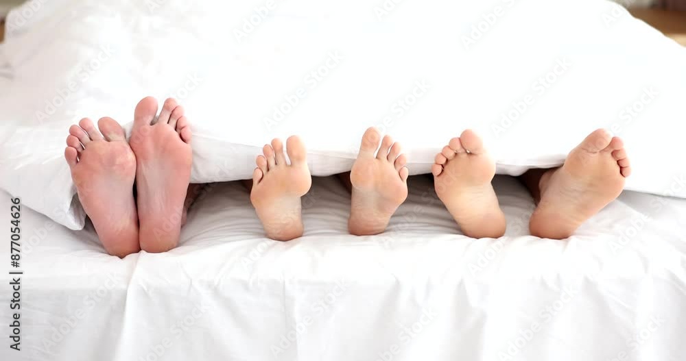 Bare feet of parents and little child moving covered with white blanket ...