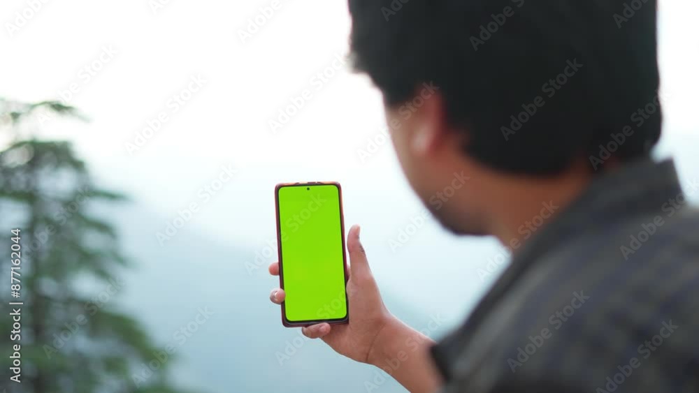 4K Over the shoulder shot of a defocused young Indian man holding ...