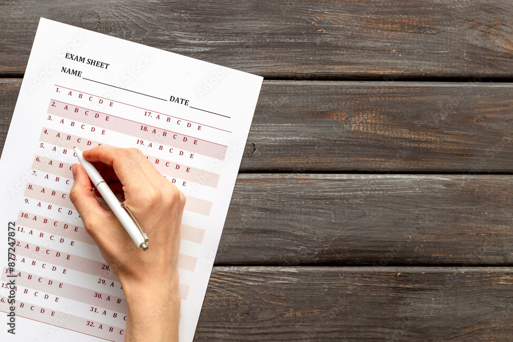 Female hand with answer exam sheet form on a table, top view. Education ...