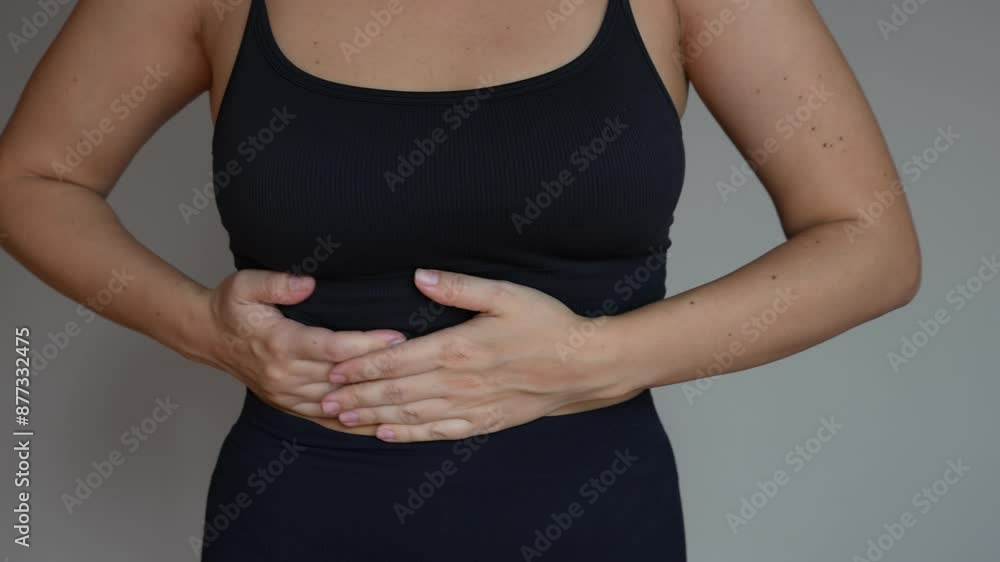 Young woman holding her side under the right rib with her hands on a ...