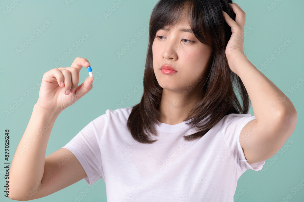 Forget taking medicine. Confused woman holds head and looks at pills on ...