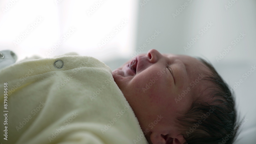 Newborn baby lying on a soft surface, dressed in a cozy cream outfit ...