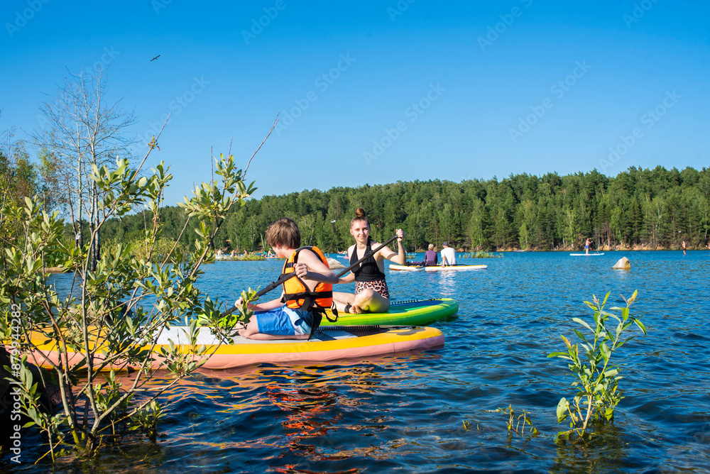 teenage girl and 11 year old boy on SUP boards on the lake. brother and ...