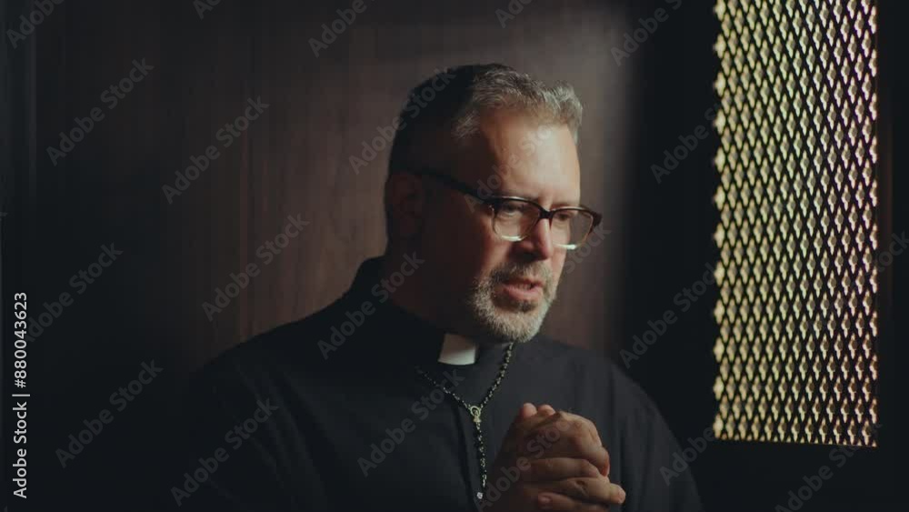 Mature Catholic priest wearing black cassock sitting inside of ...