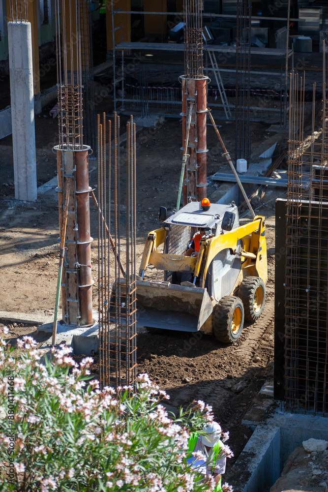 A compact excavator operates at a construction site, maneuvering ...