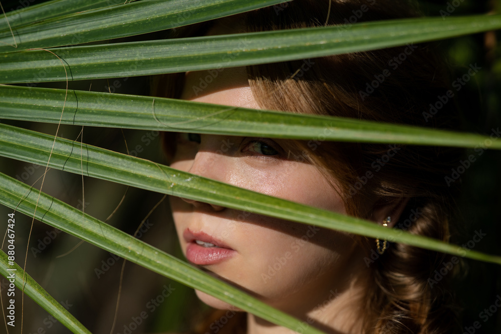 Portrait of beautiful woman with palm leaf on face. Young beautiful ...
